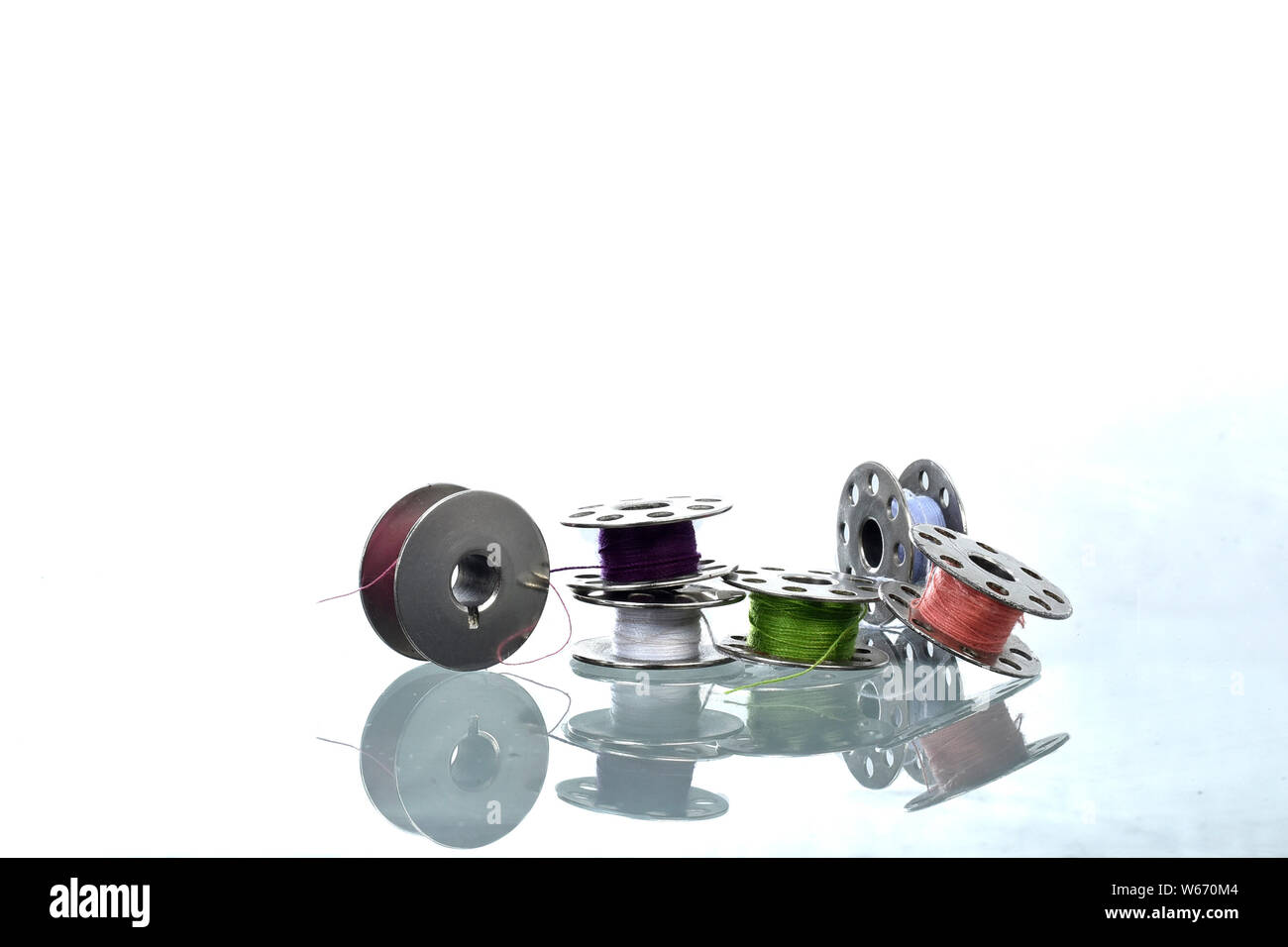 metal spool of colored threads on white background with reflection ...