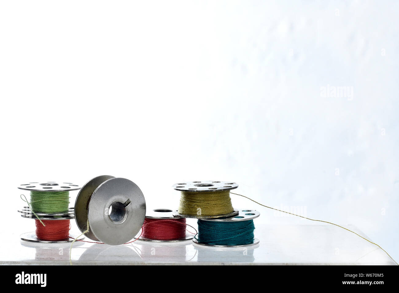 metal spool of colored threads on white background with reflection ...