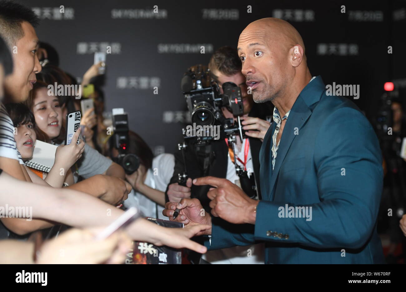American actor Dwayne Johnson signs autographs for fans as he arrives ...