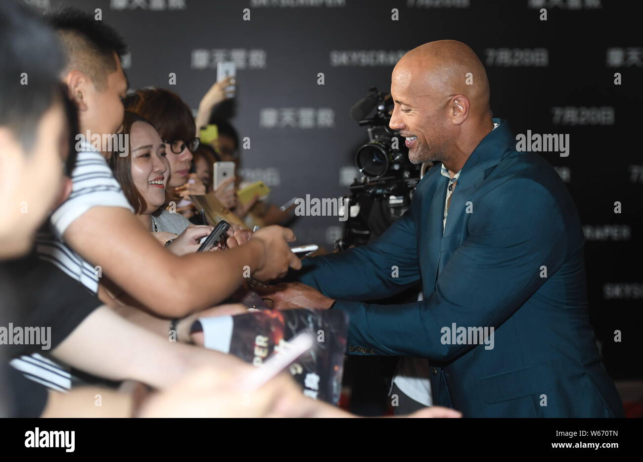 American actor Dwayne Johnson signs autographs for fans as he arrives ...