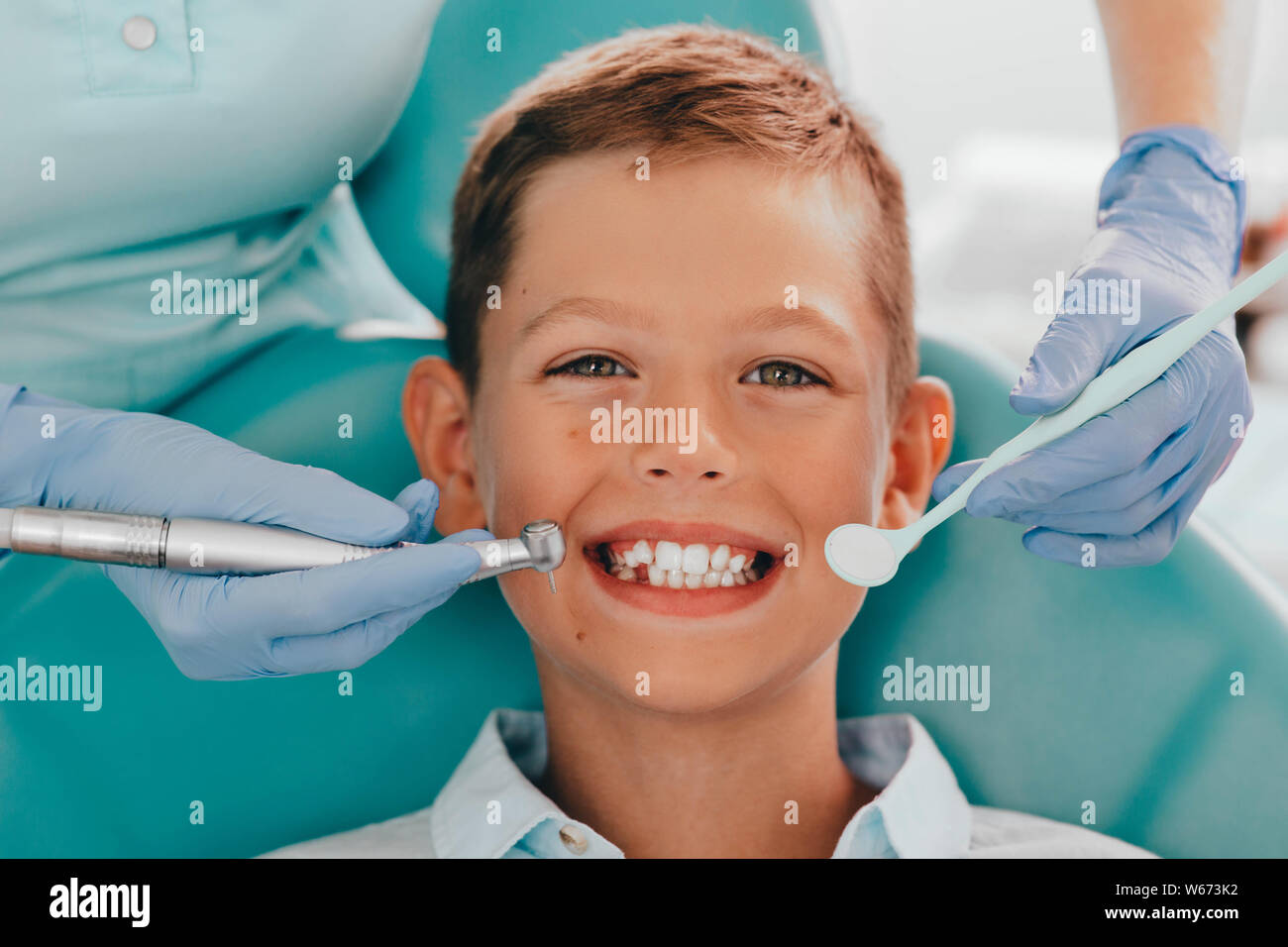 Cute boy smiling while teeth exam . Happy boy sitting in dentists chair ...