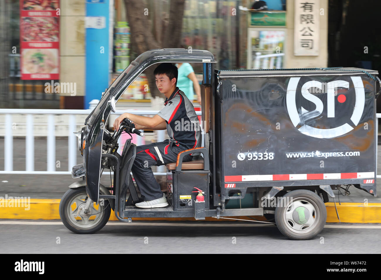 A Chinese courier drives a delivery vehicle of SF Express to delivery ...