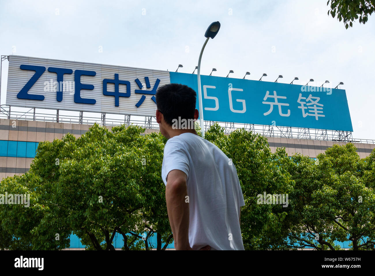 --FILE--A pedestrian walks past a signboard of ZTE on the rooftop of an ...