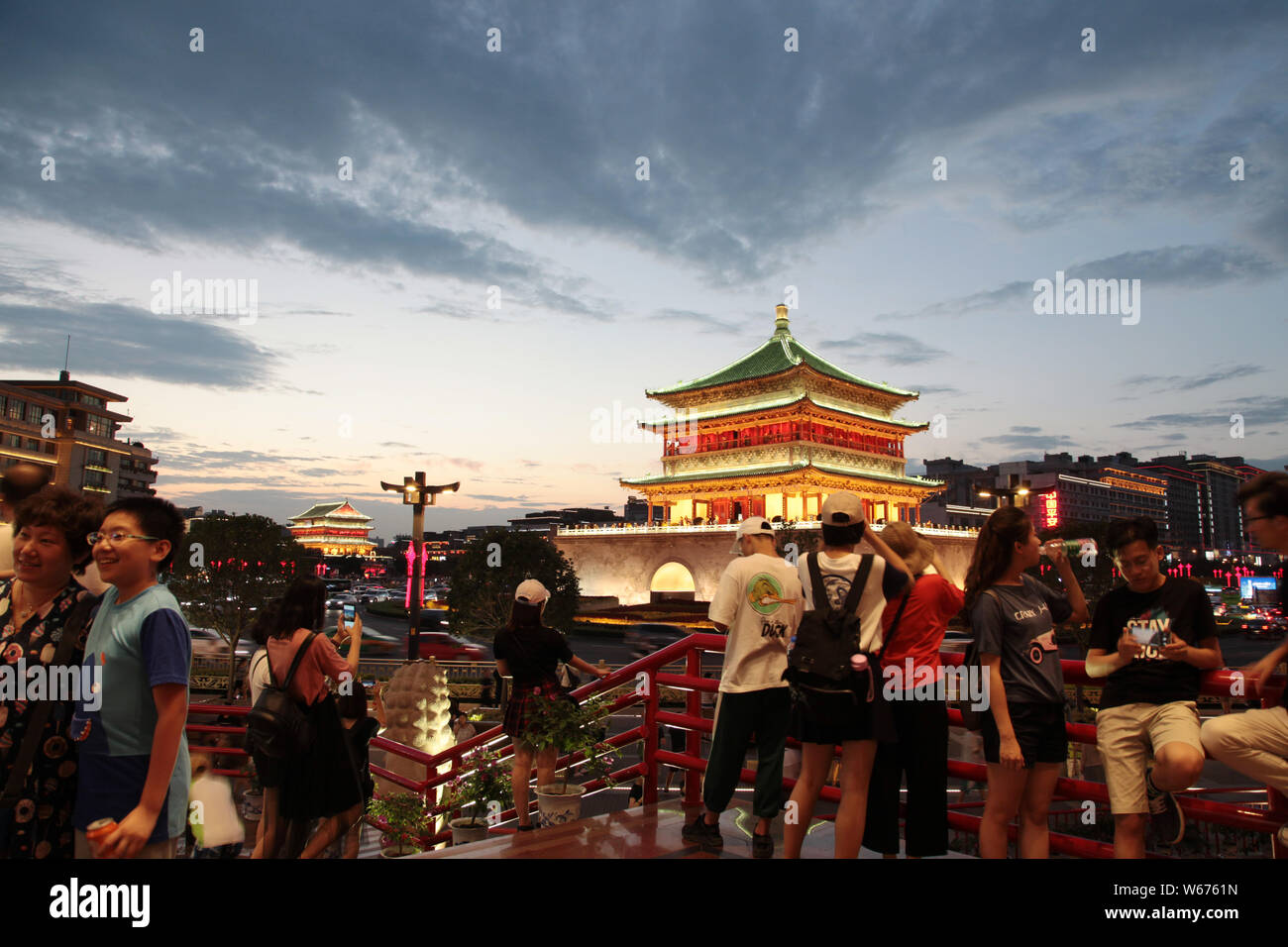 Tourists take photos of the Bell Tower after a rainfall at sunset in Xi ...