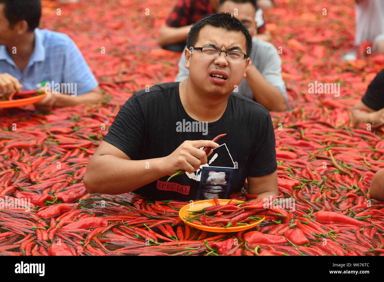 A participant sitting in a big pool filled with chili takes part in an ...