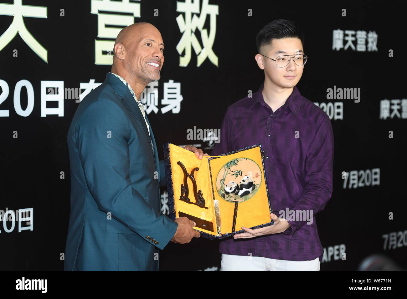 American actor Dwayne Johnson, left, receives a gift as he arrives on ...