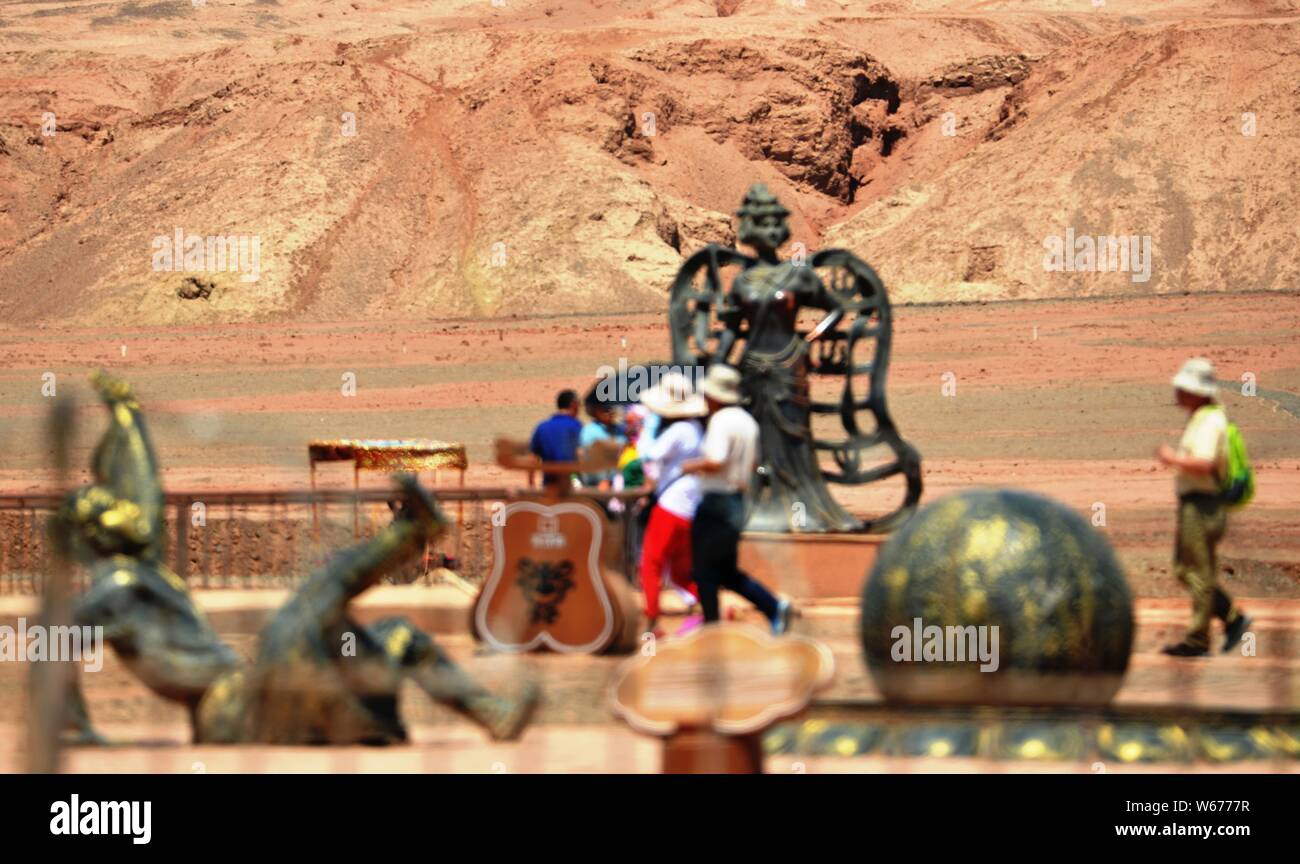 Tourists pose for photos with the landmark sculpture at the foot of the ...