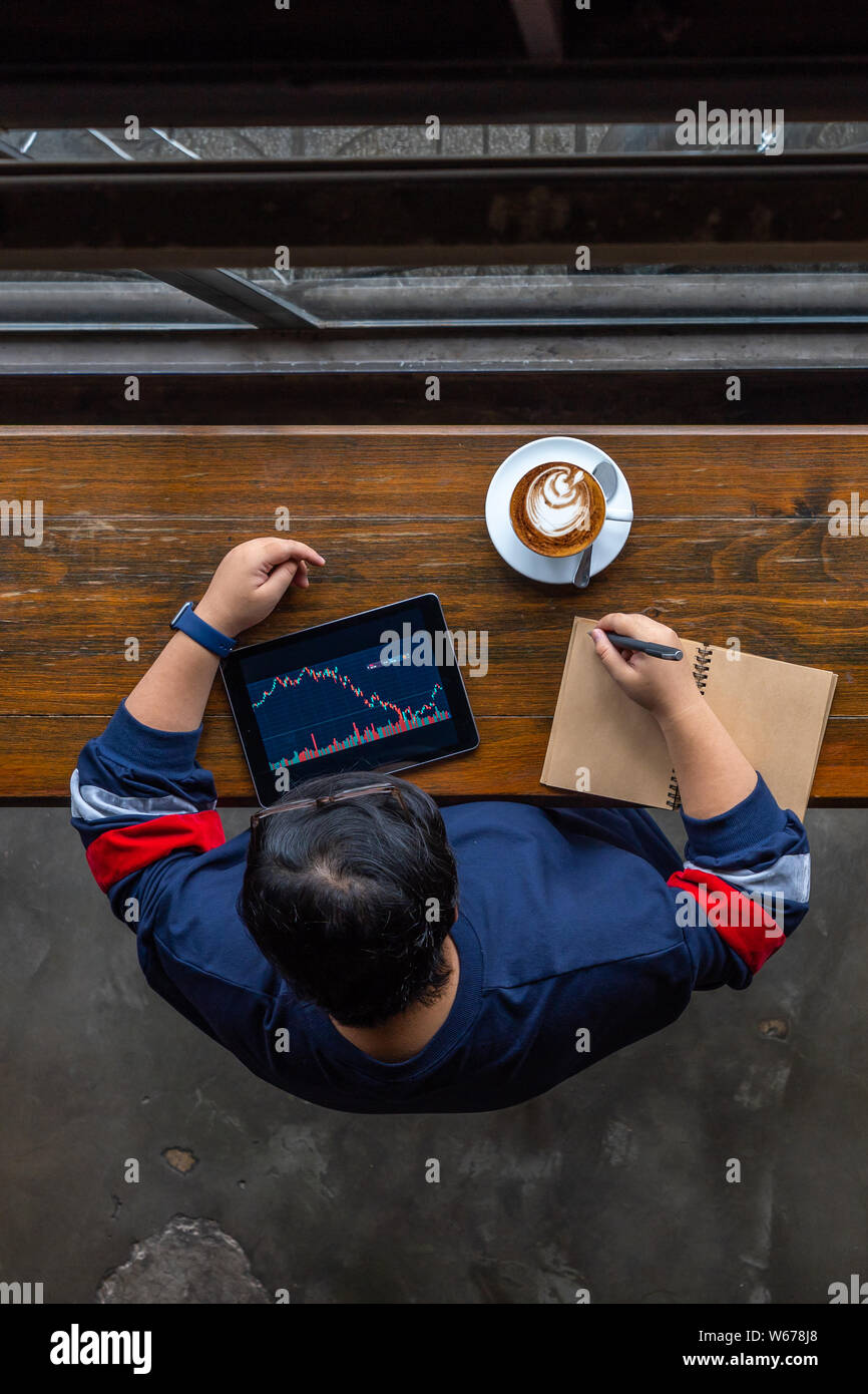 Vertical photo of Asian investor tracking stock market on tablet Stock ...