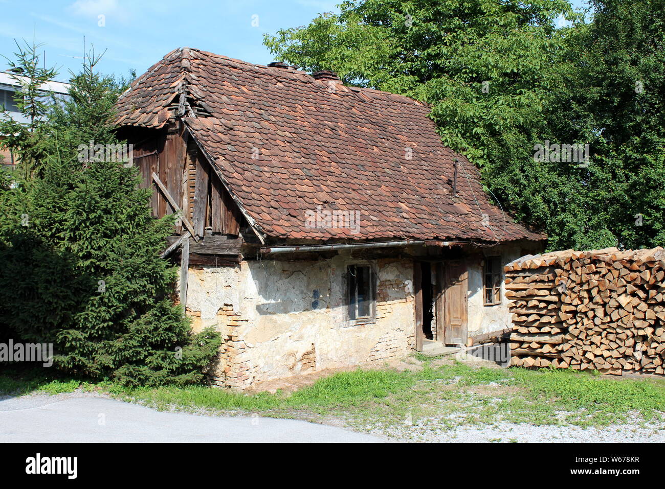 Abandoned small family house with cracked walls and dilapidated facade covered with partially ...