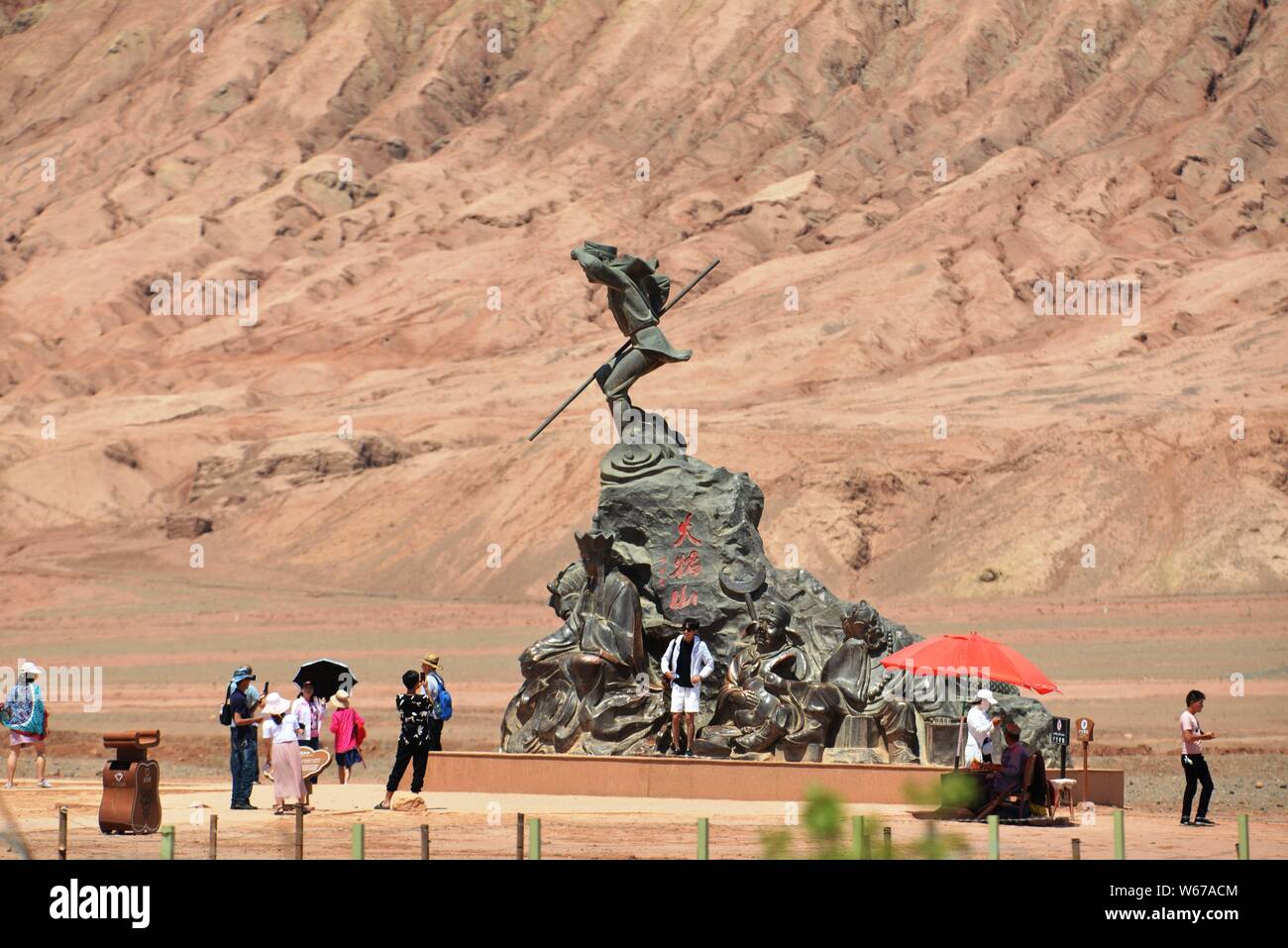 Tourists pose for photos with the landmark sculpture at the foot of the ...
