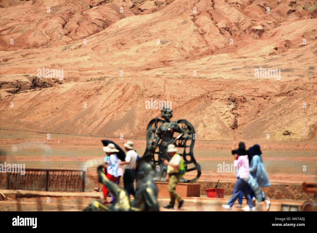 Tourists pose for photos with the landmark sculpture at the foot of the ...