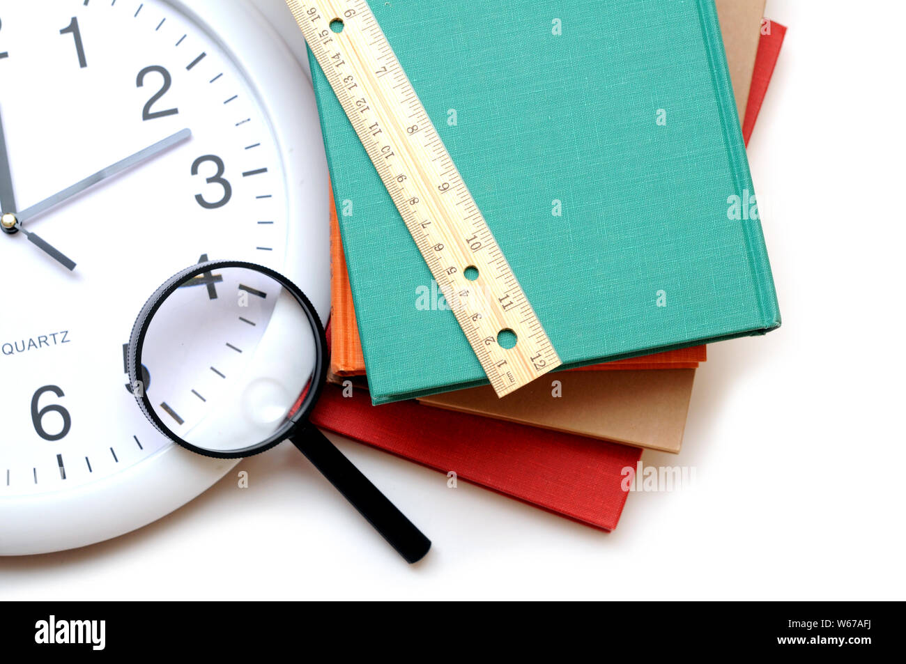 Education concept with books, magnifying and clock Stock Photo - Alamy