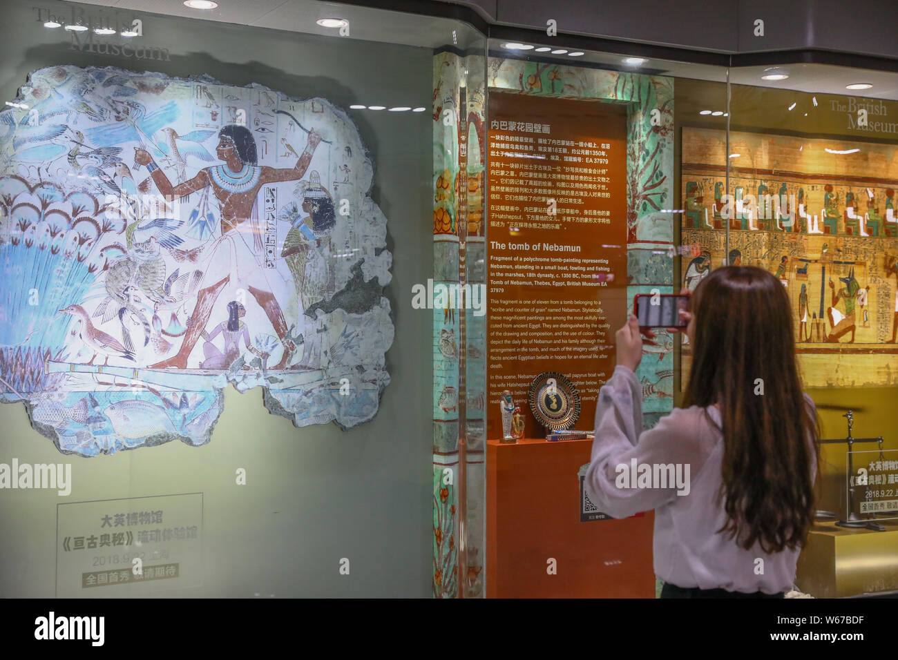 A passenger takes photos of a reproduction of a mural from the tomb ...