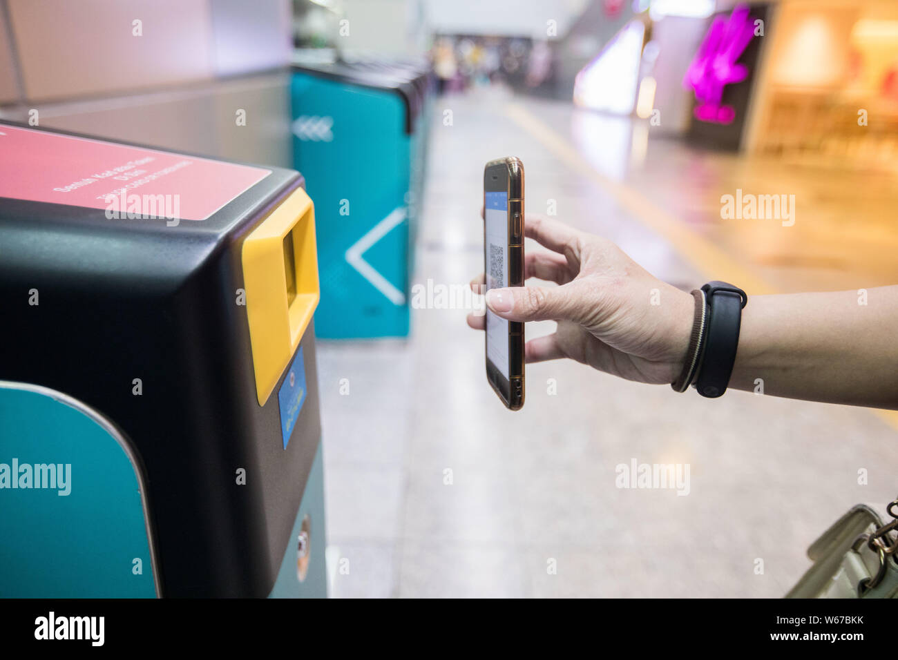 A passenger puts her smartphone near a turnstile to have the QR code on ...