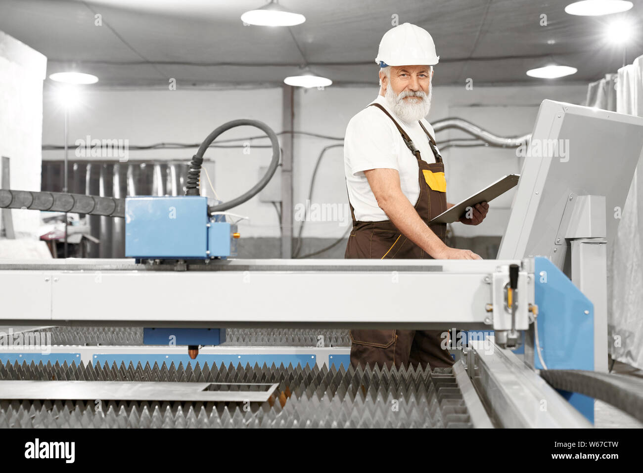 Front view of smiling male engineer looking at camera and posing while ...