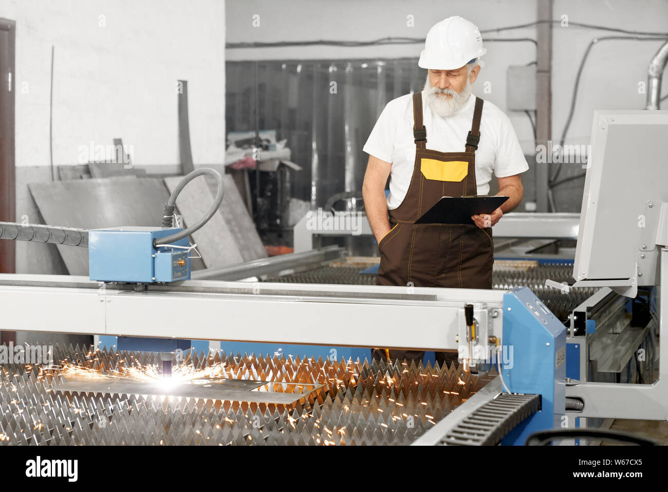 Professional engineer in uniform and helmet controlling process of ...