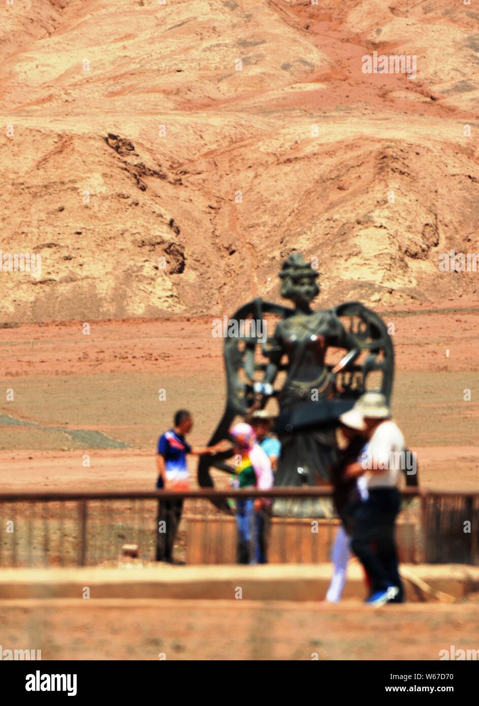 Tourists pose for photos with the landmark sculpture at the foot of the ...