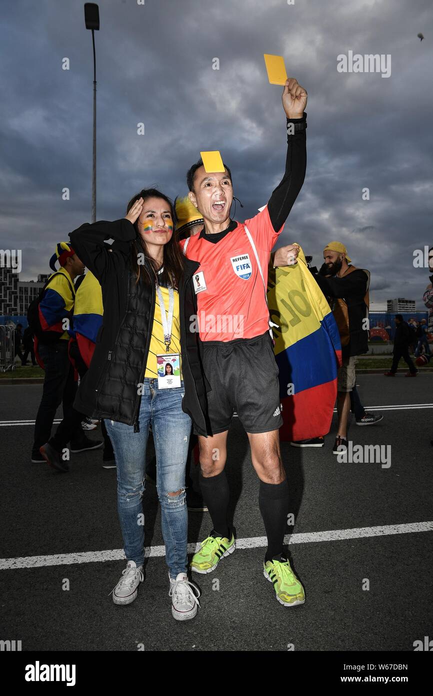 A Japanese fan who cosplays a referee holding up a yellow card poses ...