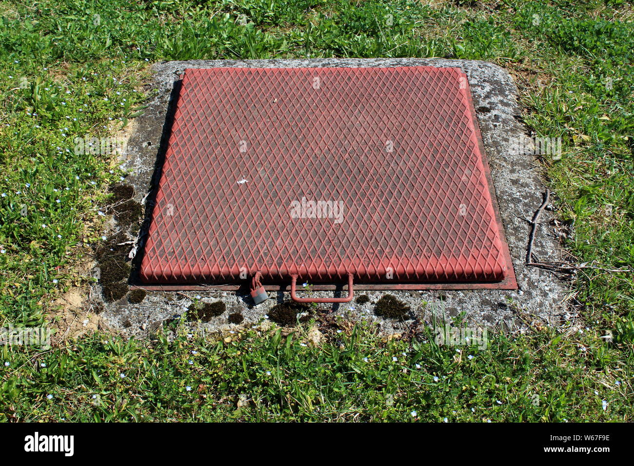 Dilapidated rectangular metal manhole cover mounted on top of concrete ...