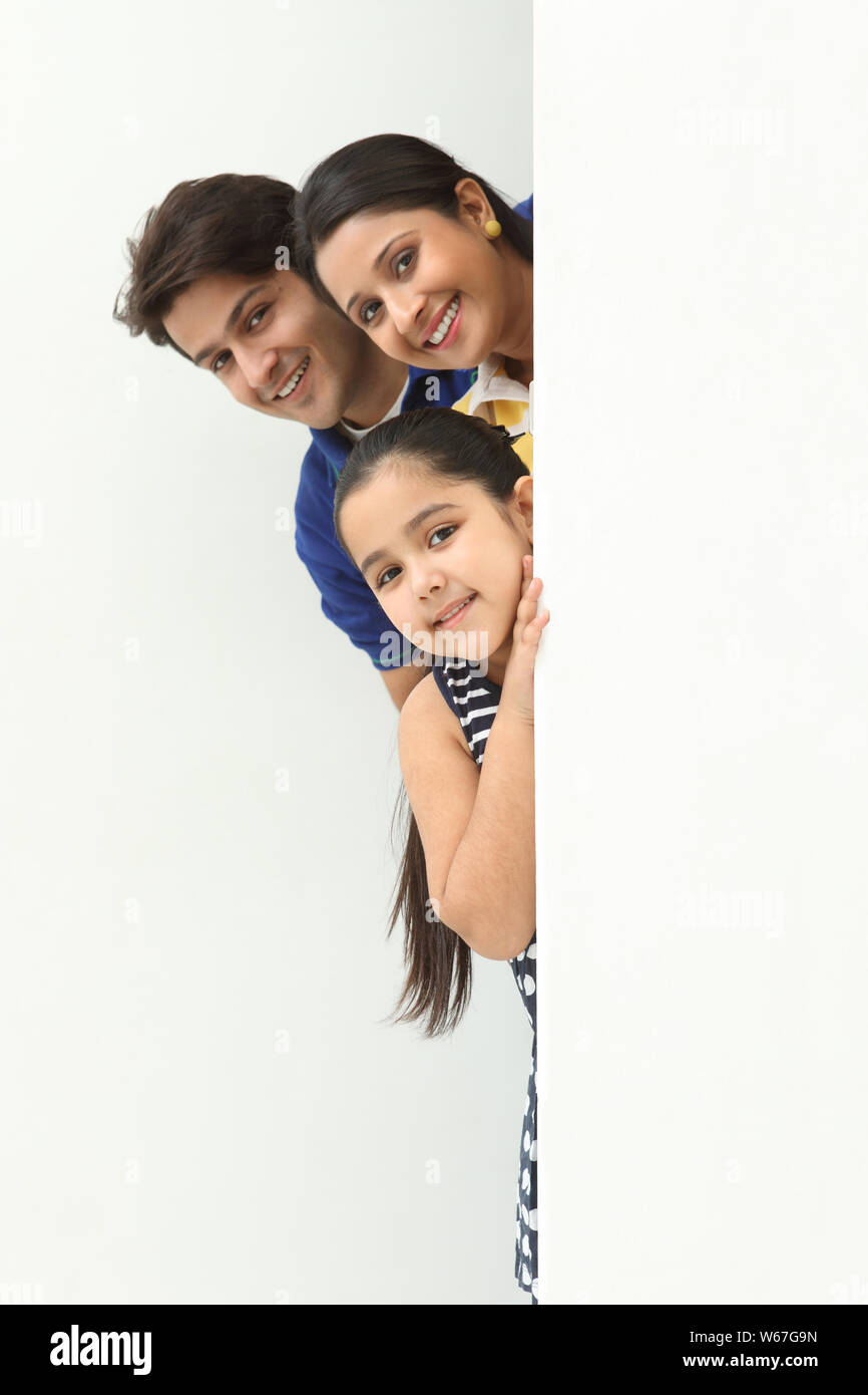 Family hiding behind a placard Stock Photo - Alamy