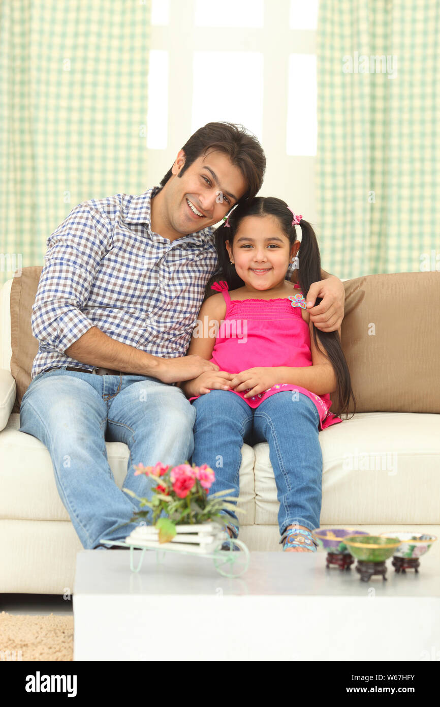 Man sitting on a couch with his daughter smiling Stock Photo - Alamy