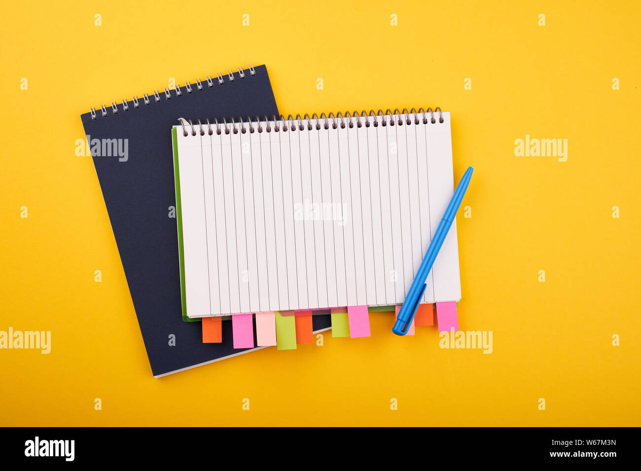 Notepad with color stickers and blue pen on yellow background Stock ...