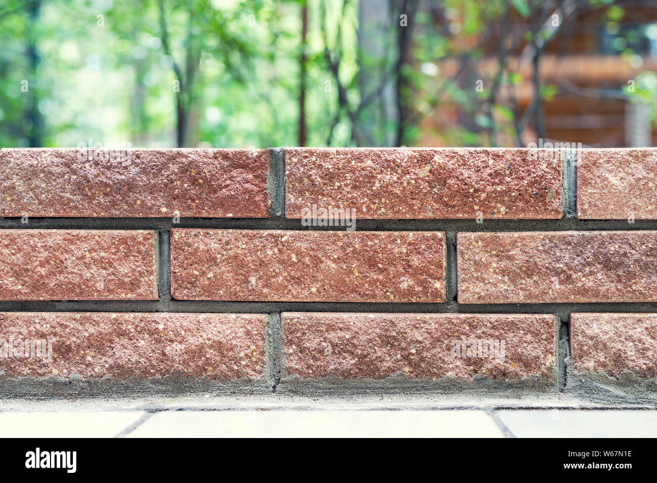 Straight lines of new fresh brickwork wall with blurred park or house ...
