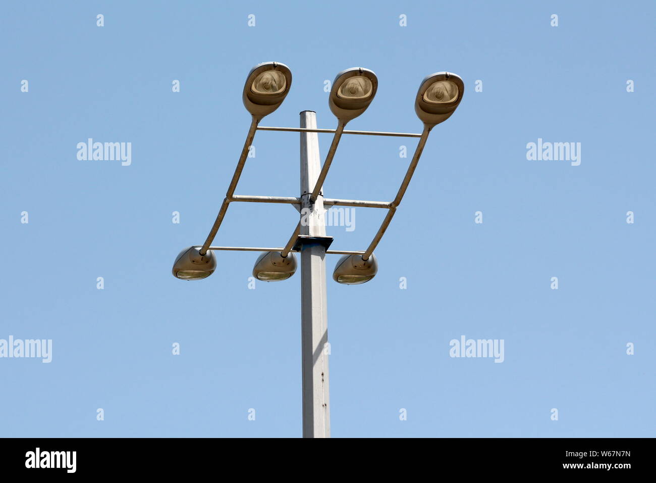 Tall strong metal utility pole with six large modern light reflectors ...