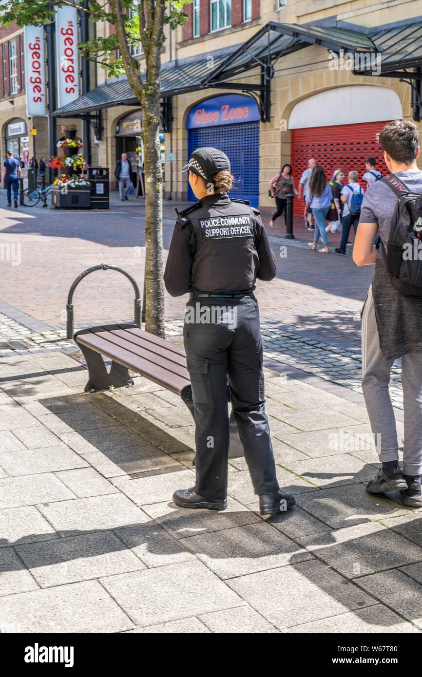 Police community service officer speaking to youths in the town centre ...