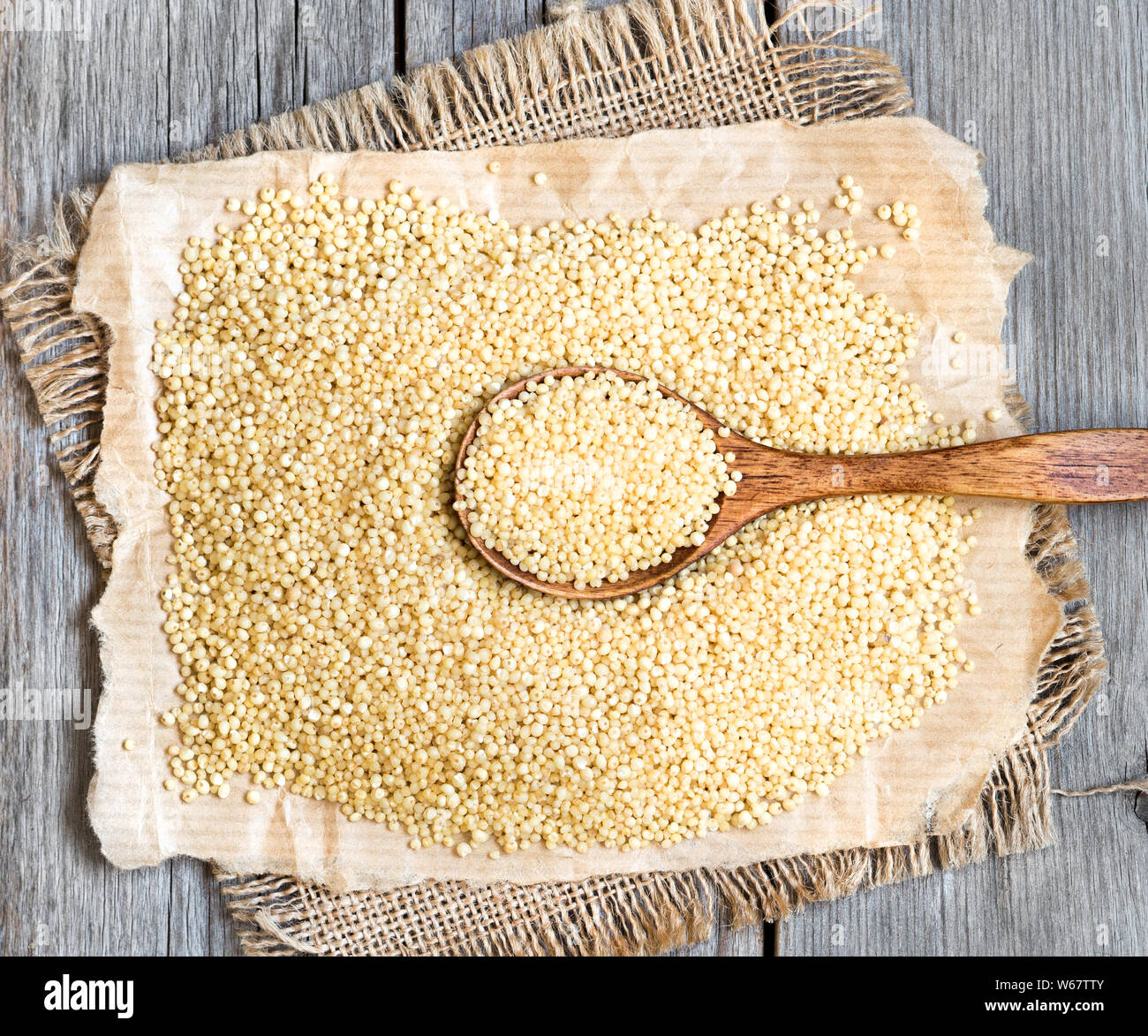 Millet on a wooden table with a spoon Stock Photo - Alamy