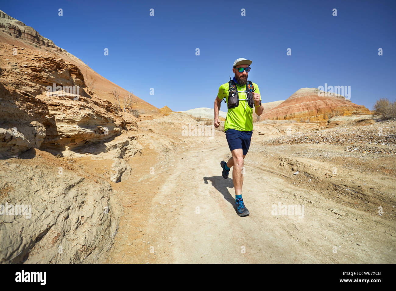 Runner athlete with beard running on the wild trail at clay mountains ...