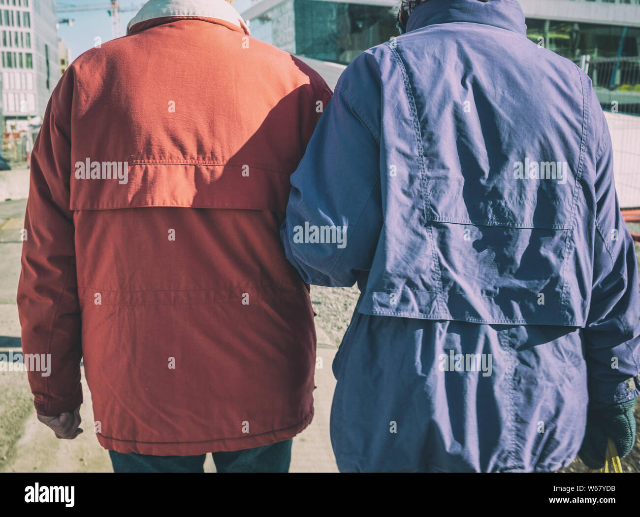 Senior couple rear cuddling arm walking in the city on winter season ...