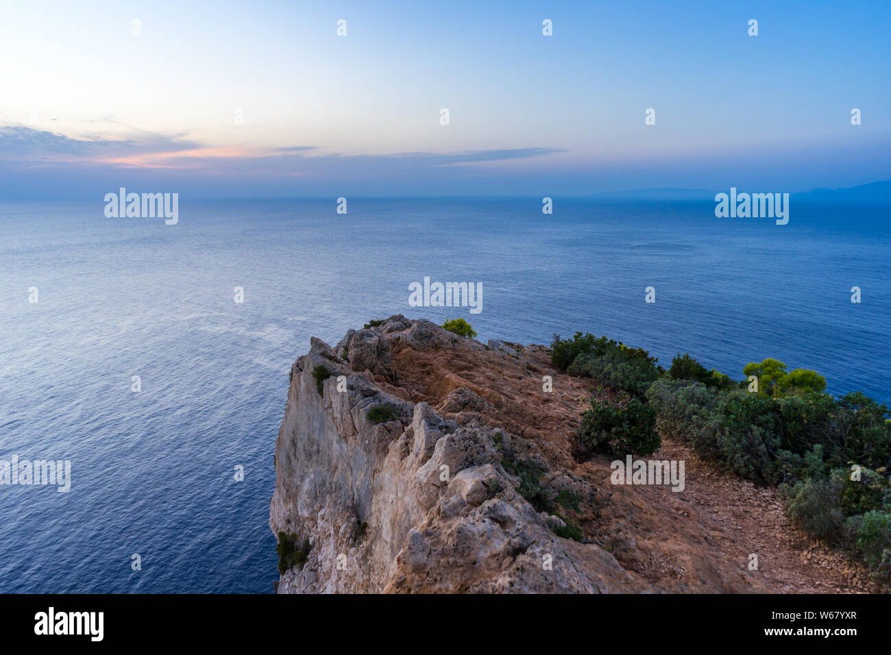 Endless blue ocean water horizon behind top of a mountain in blue hour ...