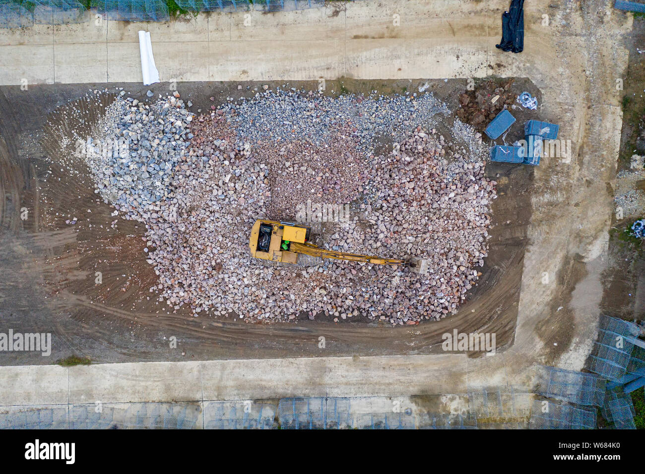 Aerial view, Yellow backhoe loader on heap rocks at construction site ...
