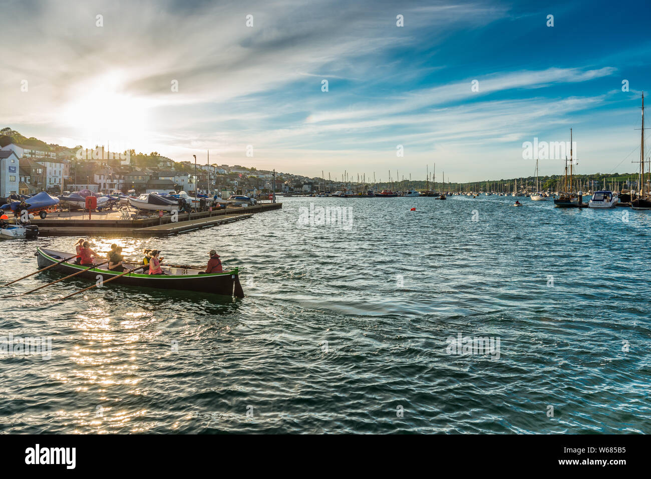 Female rowers on Falmouth harbour with a low sun overhead. Cornwall ...