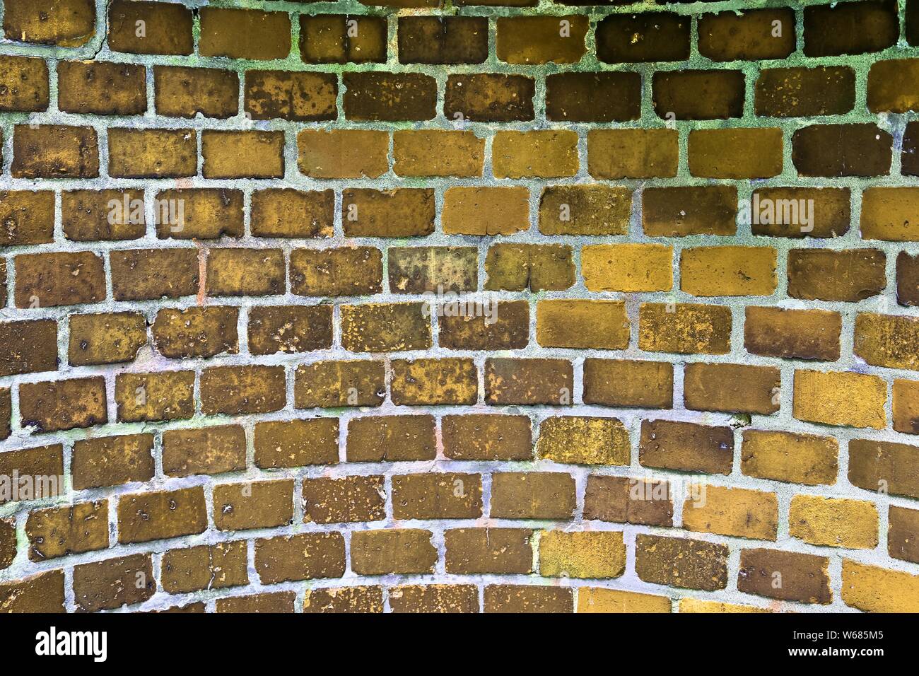 Yellow brick walls with old and weathered stones and cracks im high ...