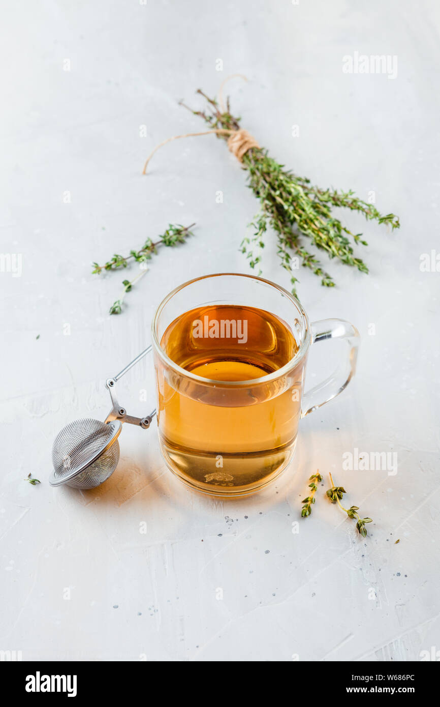 Transparent glass cup of herbal tea with thyme and sprigs of thyme tied ...