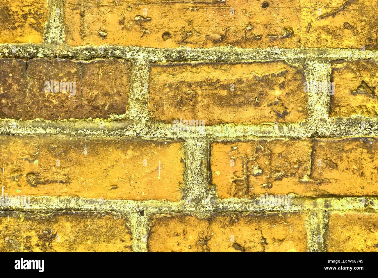 Yellow brick walls with old and weathered stones and cracks im high ...