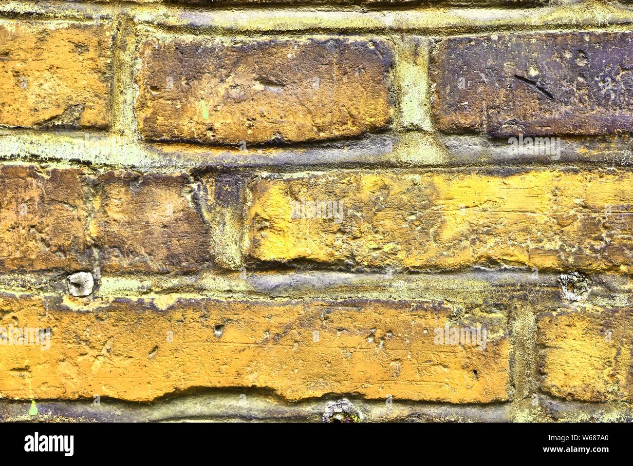 Yellow brick walls with old and weathered stones and cracks im high ...
