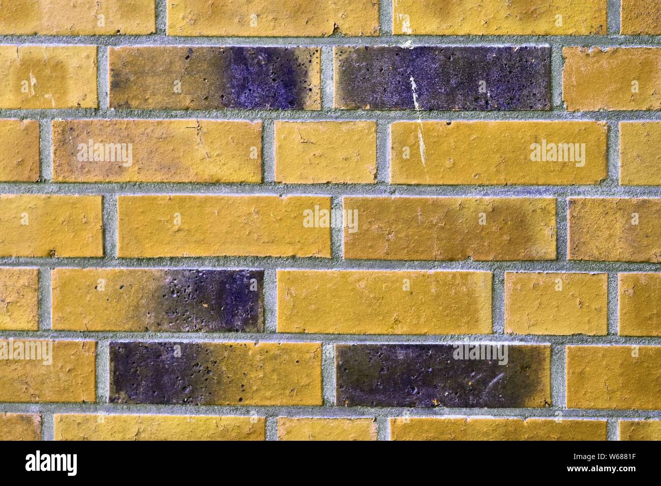 Yellow brick walls with old and weathered stones and cracks im high ...