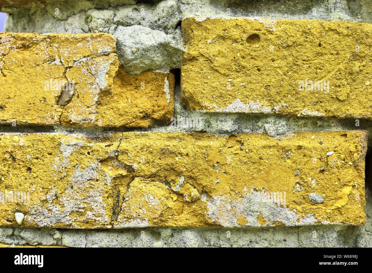 Yellow brick walls with old and weathered stones and cracks im high ...