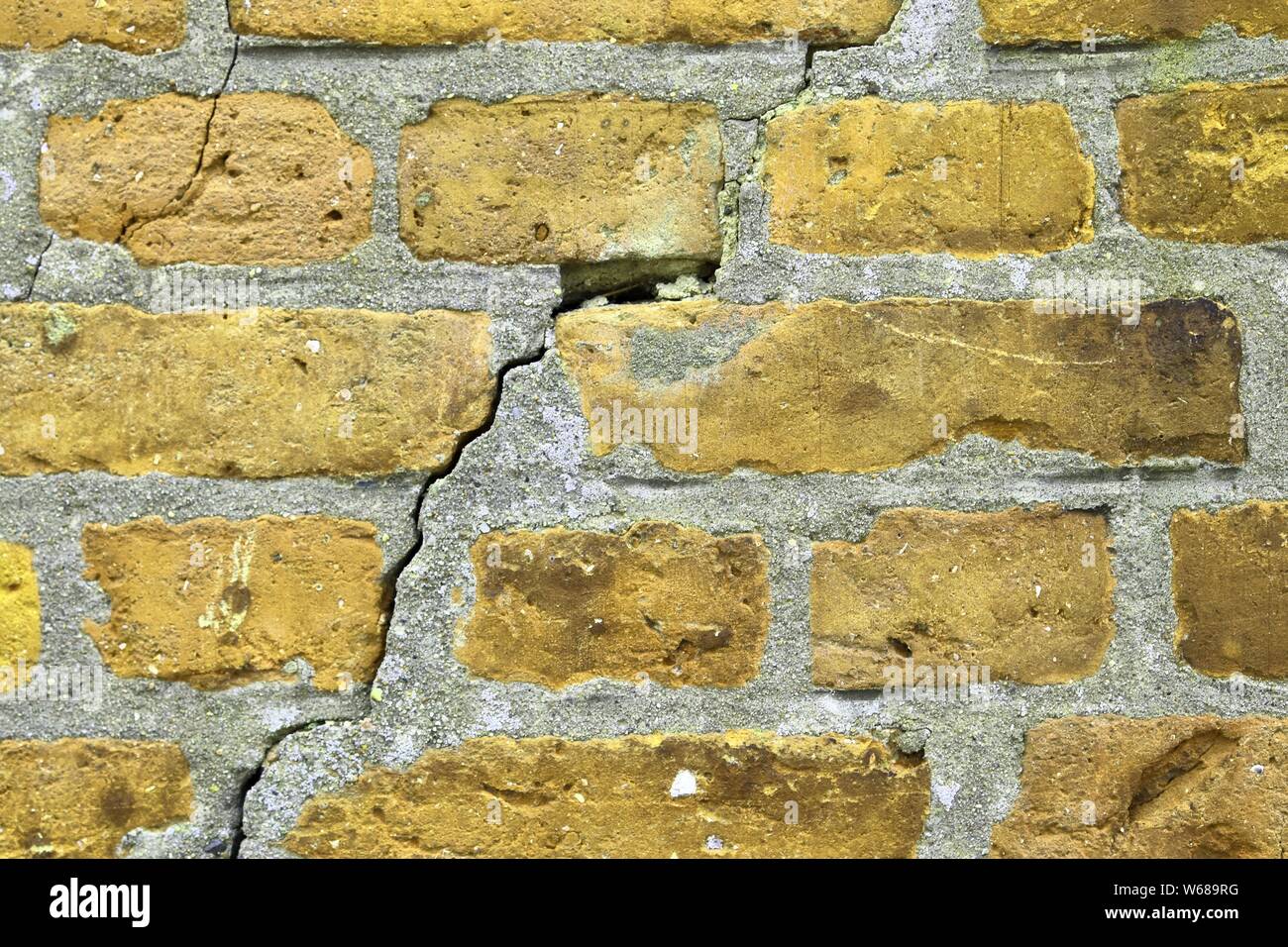 Yellow brick walls with old and weathered stones and cracks im high ...