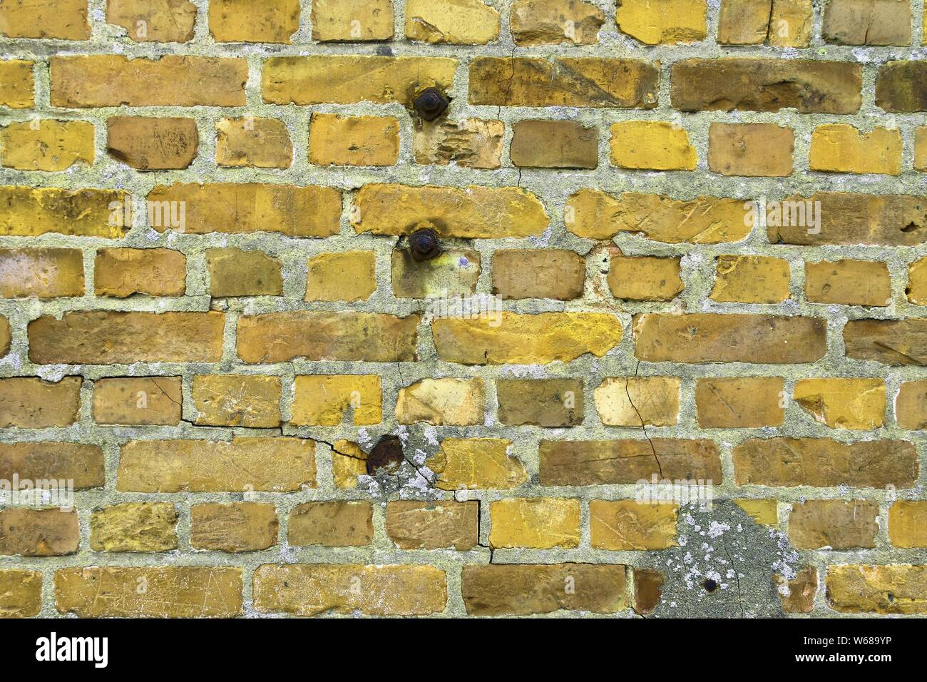 Yellow brick walls with old and weathered stones and cracks im high ...