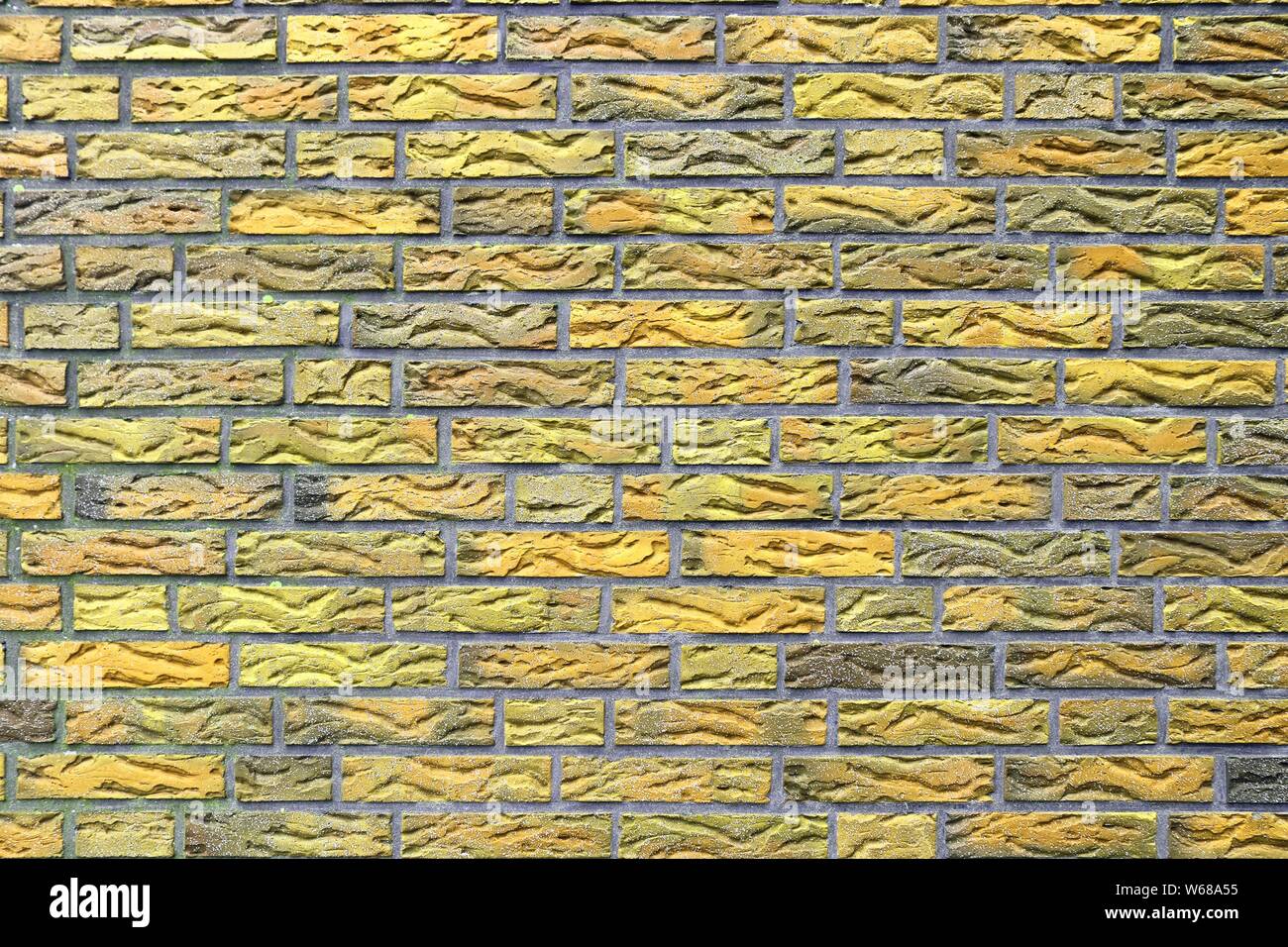 Yellow brick walls with old and weathered stones and cracks im high ...