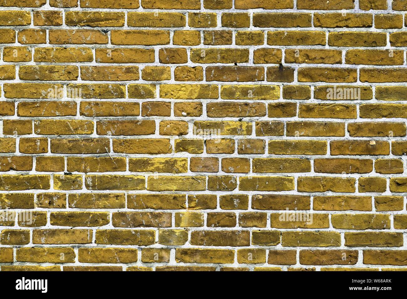 Yellow brick walls with old and weathered stones and cracks im high ...