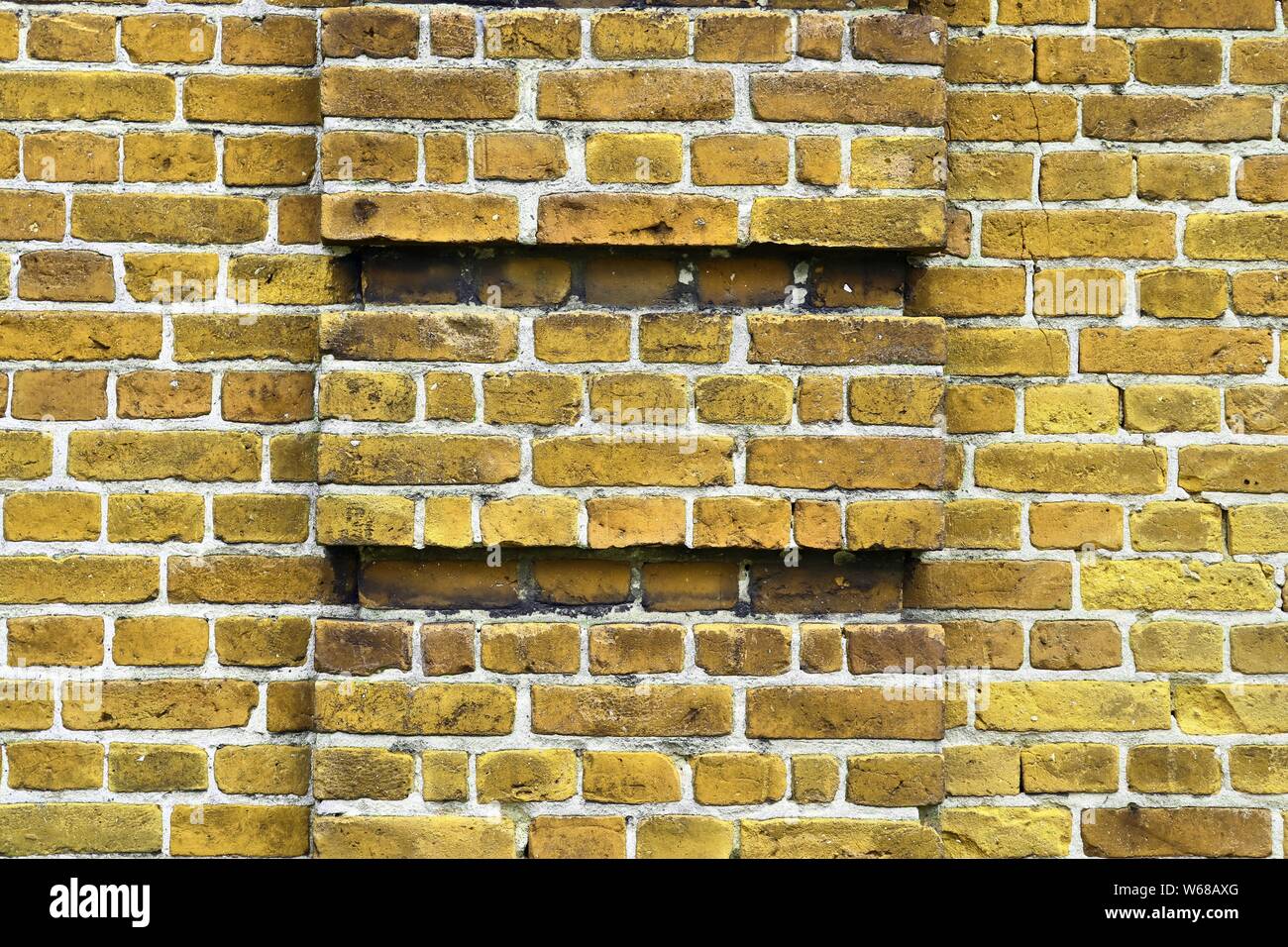 Yellow brick walls with old and weathered stones and cracks im high ...