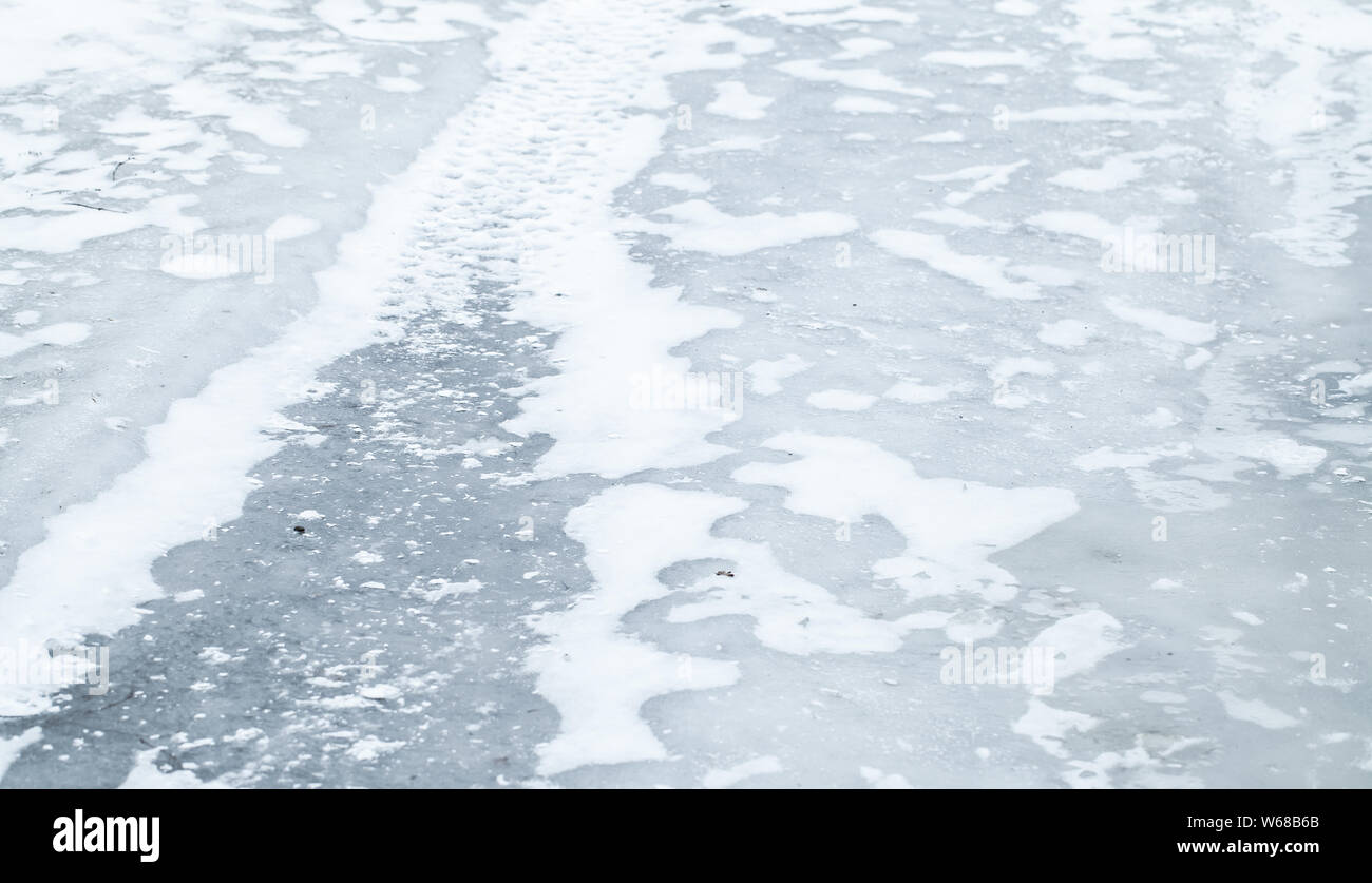 Winter transportation background with tire track on icy road covered ...