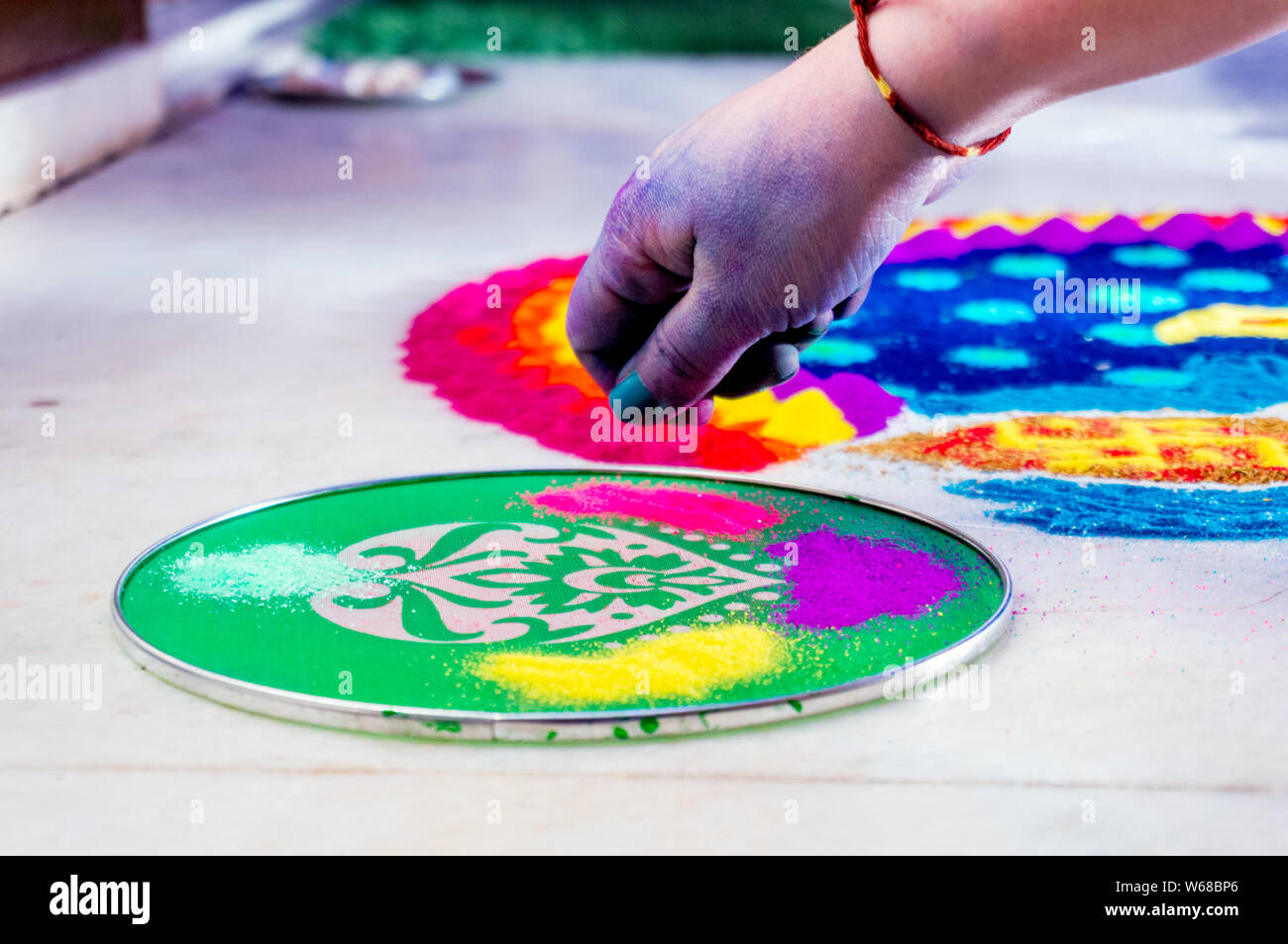 Hand of young indian girl making rangoli from colored powder on diwali ...