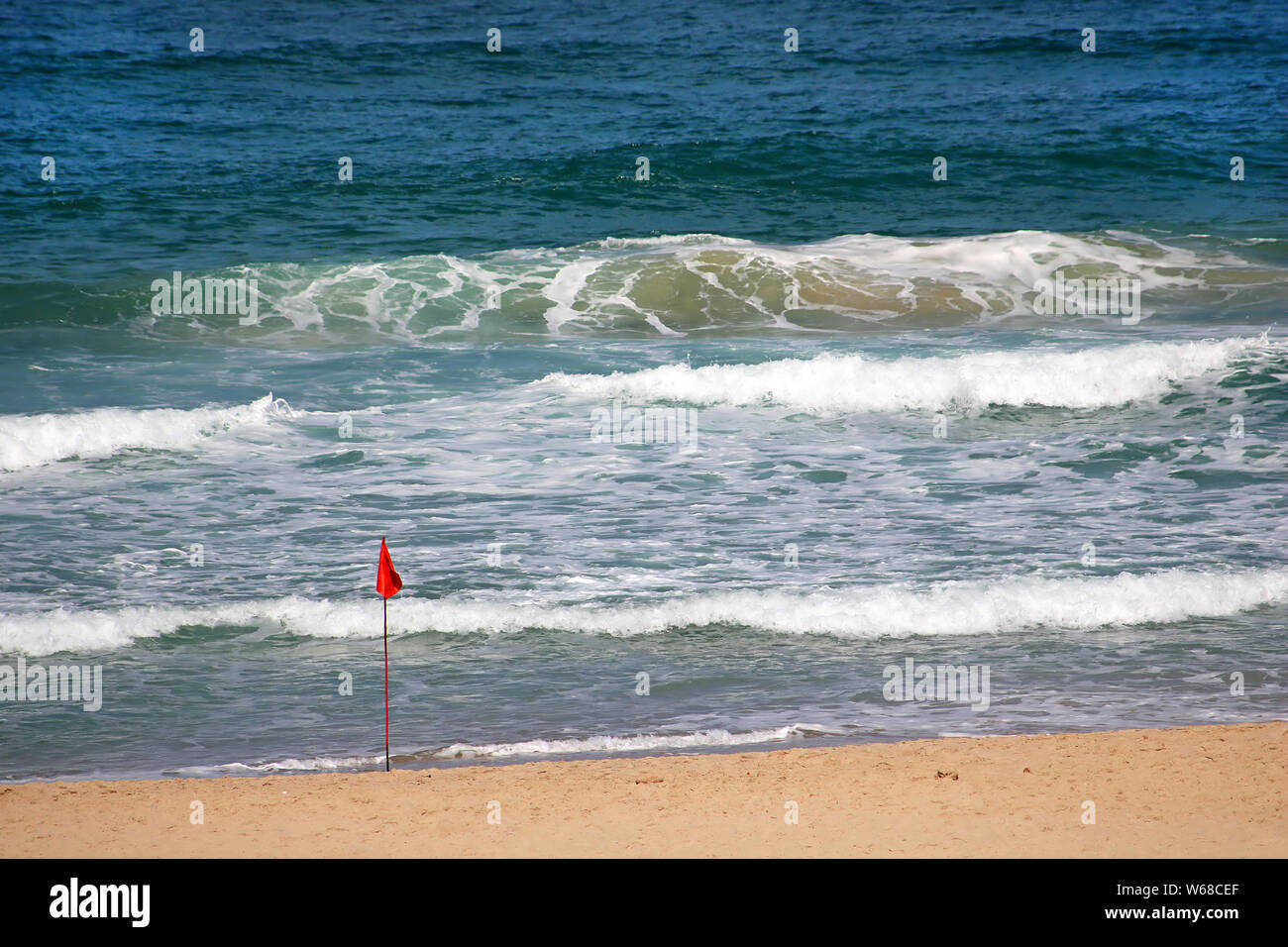 Red flag on sand beach for warning of dangerous of swimming in the sea ...