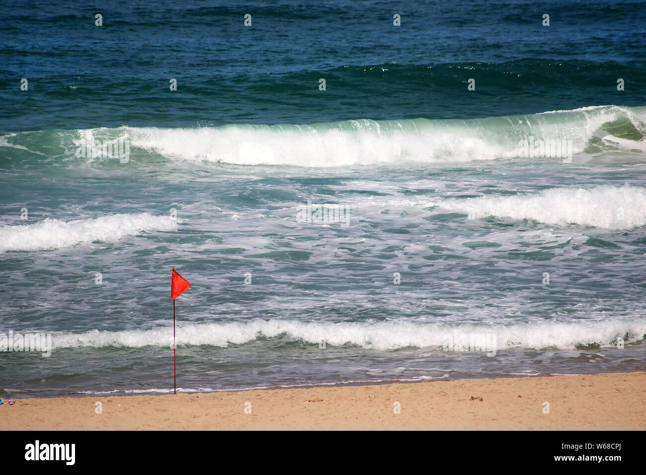 Red flag on sand beach for warning of dangerous of swimming in the sea ...